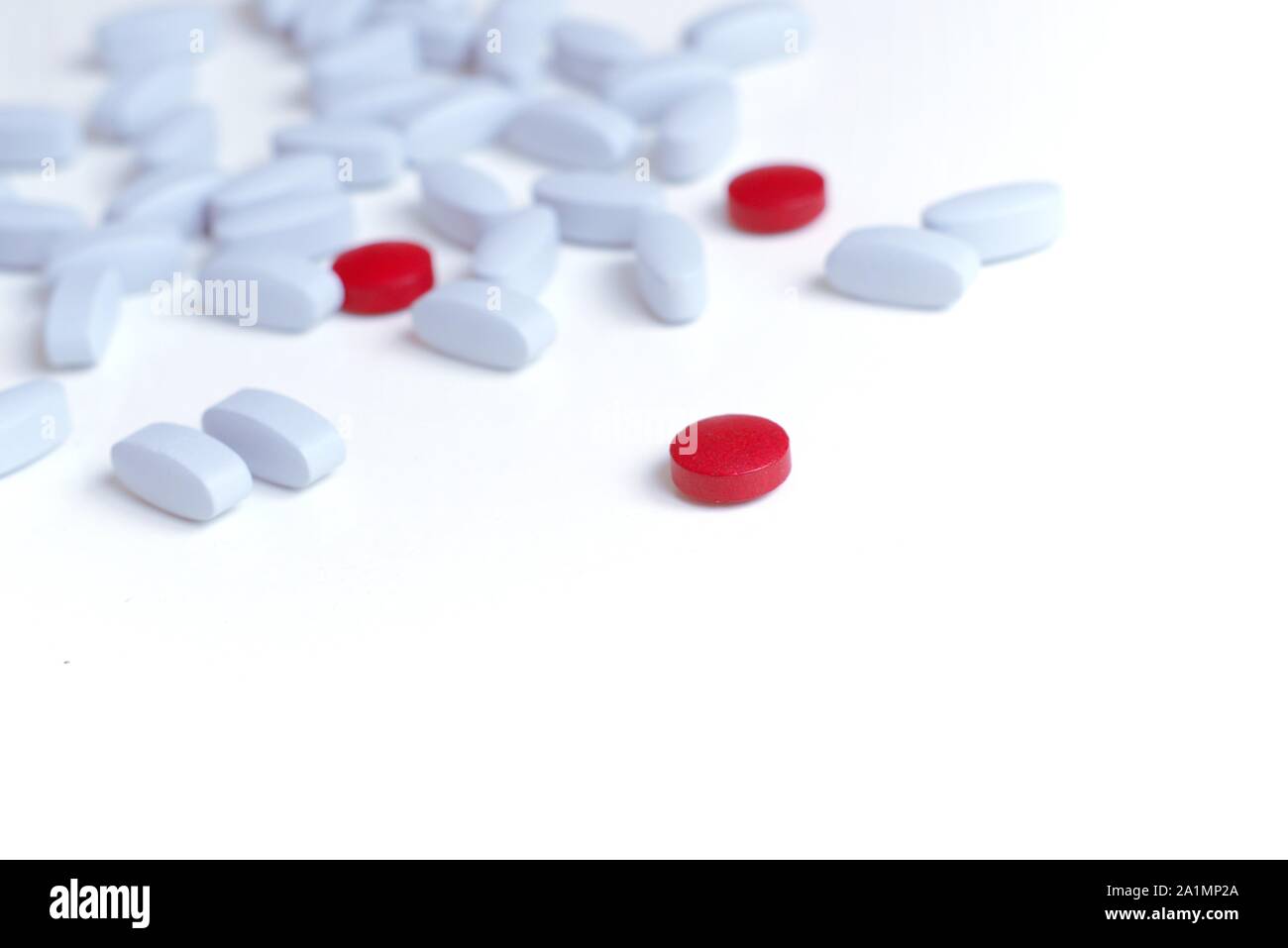 Single red pill shown prominently among light blue pills on white ...