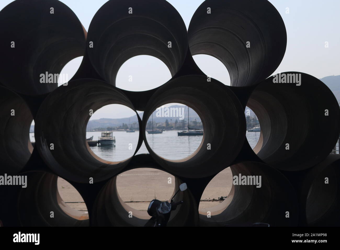 view through some large open ended cylinder in kos town harbour Stock ...