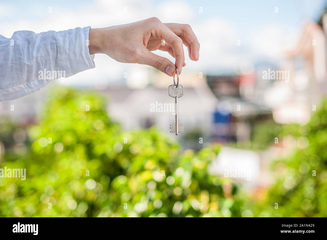 man holding key to the house on background of houses in the city. Deal ...