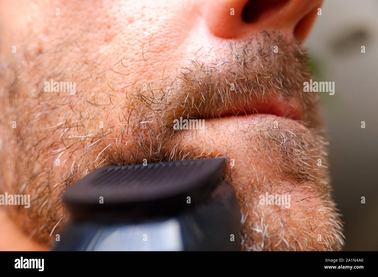 A man shaves his beard using an electric razor Stock Photo - Alamy