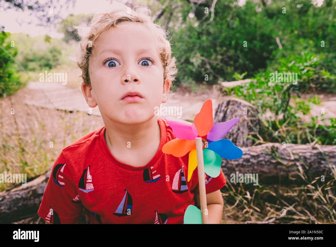 Child with a look of wonder and strangeness when discovering a pinwheel ...