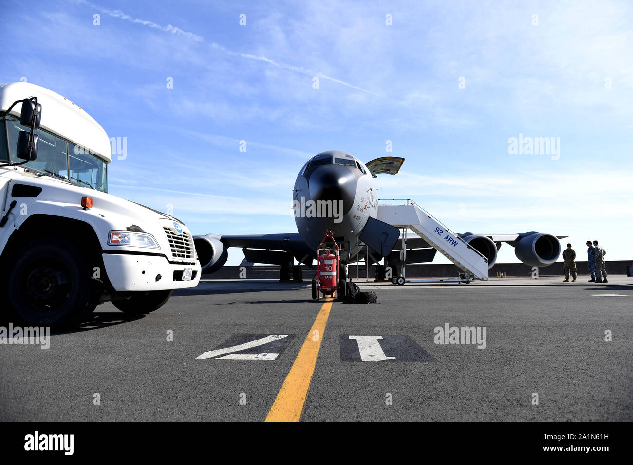 A KC-135 Stratotanker and a school bus are parked on the flight line at ...