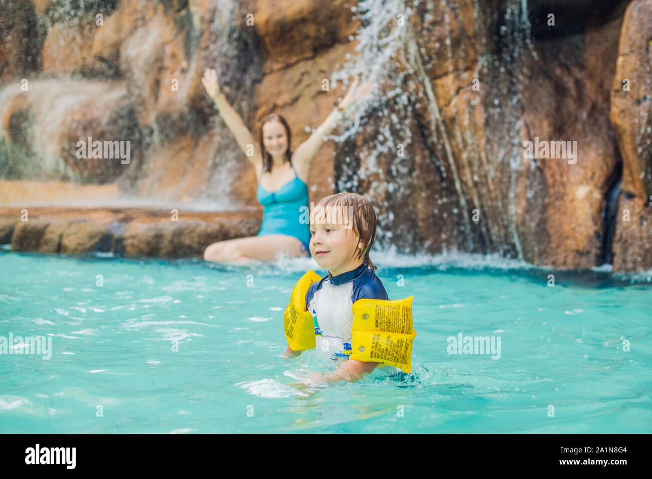 Mother and son relaxing under a waterfall in aquapark Stock Photo - Alamy