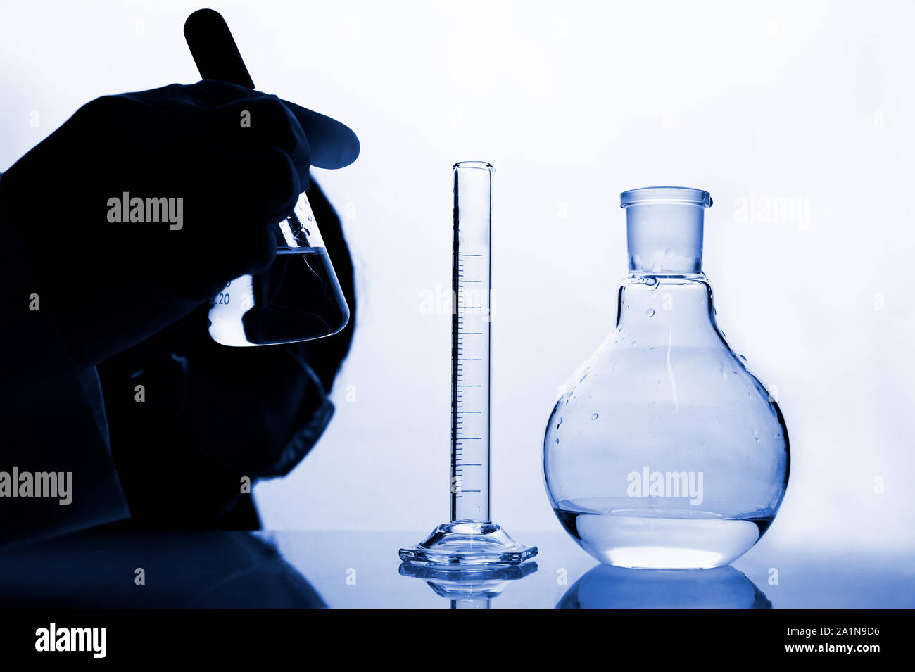 hand of scientist and chemical glass flask with cylinder in blue ...