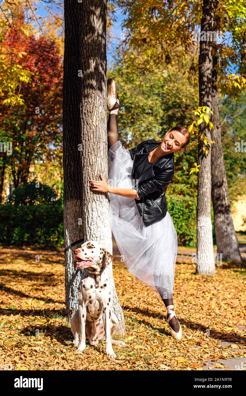 Ballerina with Dalmatian dog in the golden autumn park. Woman ballerina ...