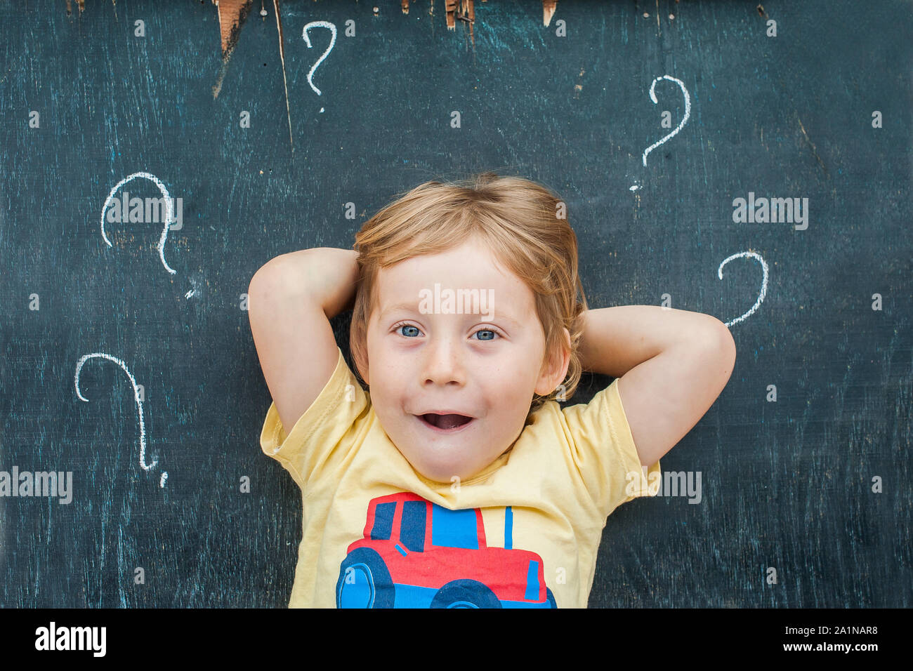 Top view of a little blond kid boy with question mark on blackboard ...