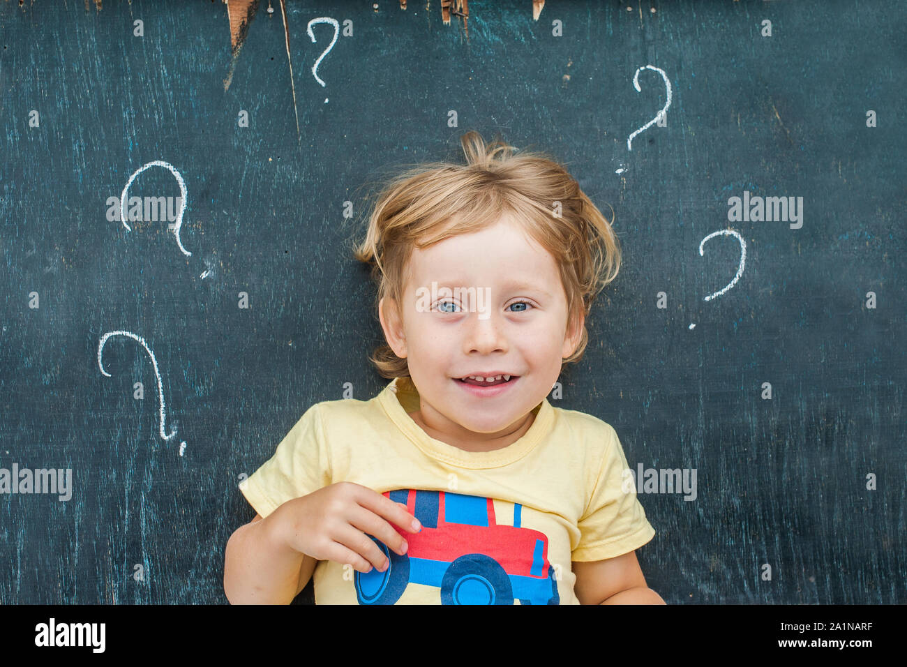 Top view of a little blond kid boy with question mark on blackboard ...