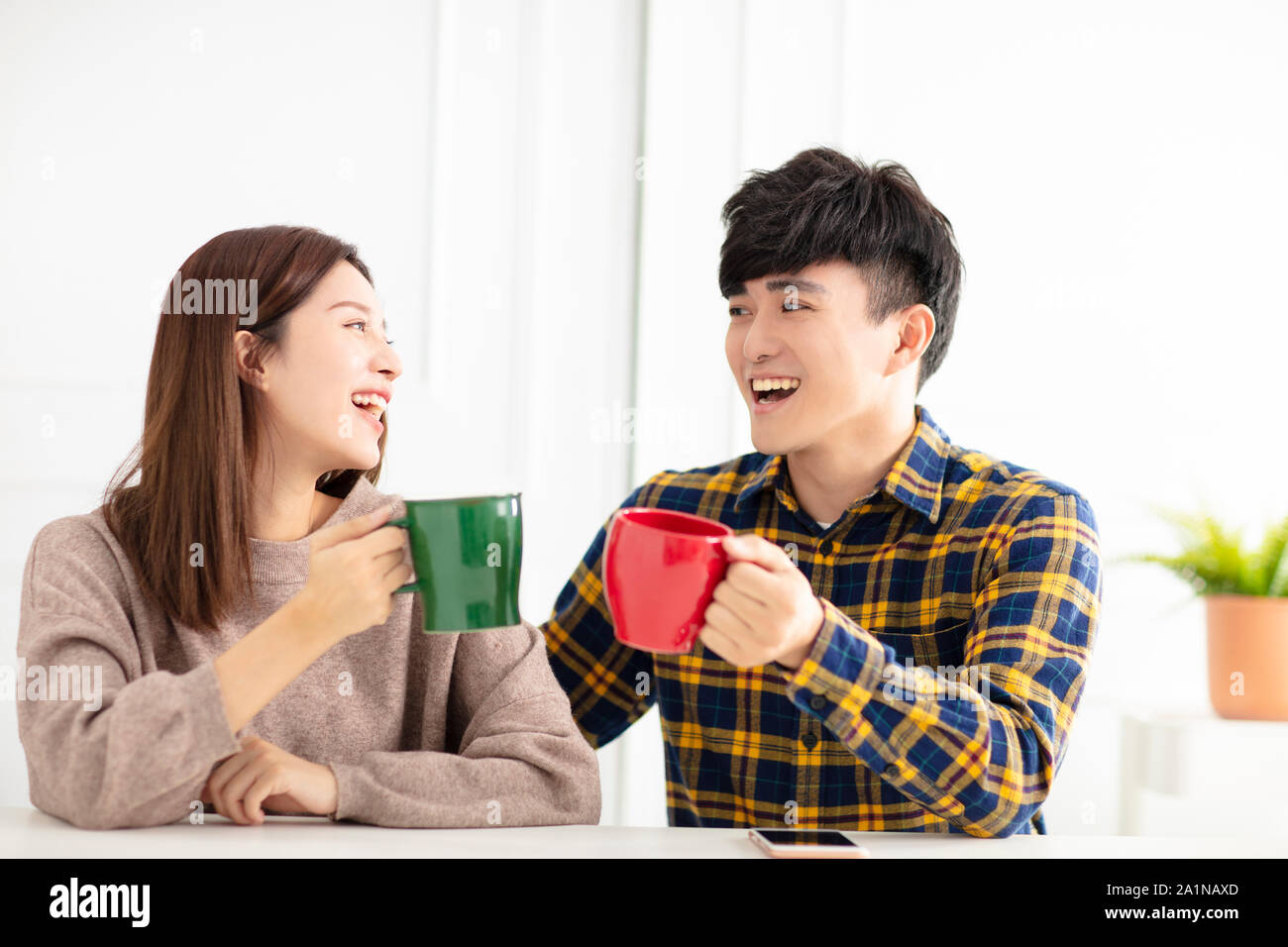 Happy young couple talking and laughing, drinking tea Stock Photo - Alamy