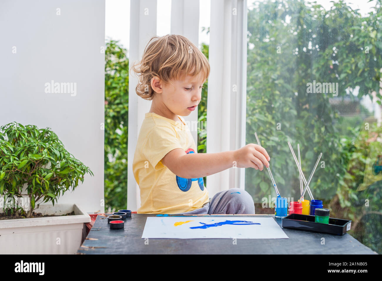 Cute little boy painting with colorful paints Stock Photo - Alamy