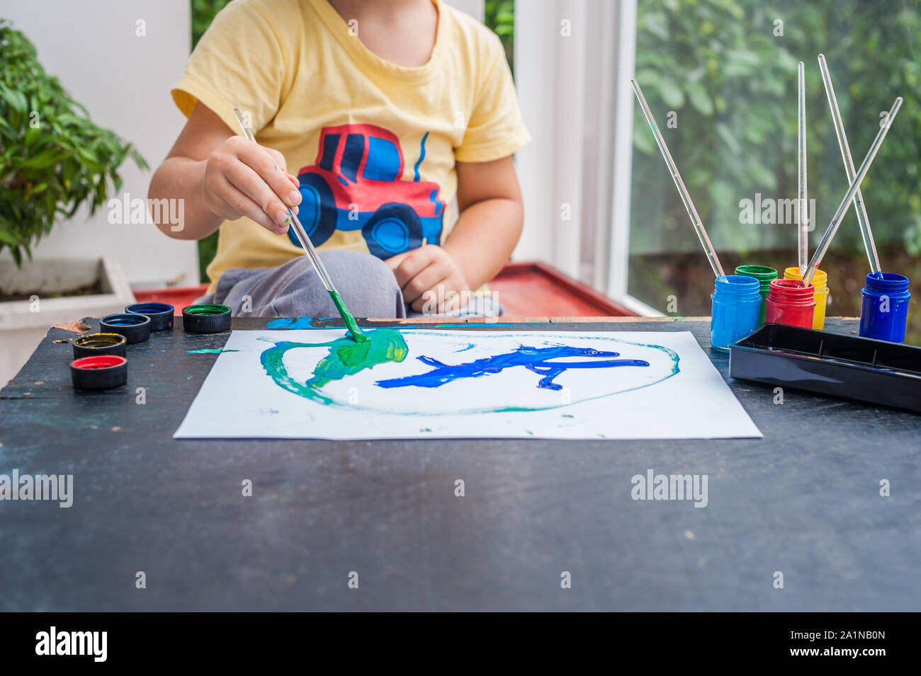 Cute little boy painting with colorful paints Stock Photo - Alamy