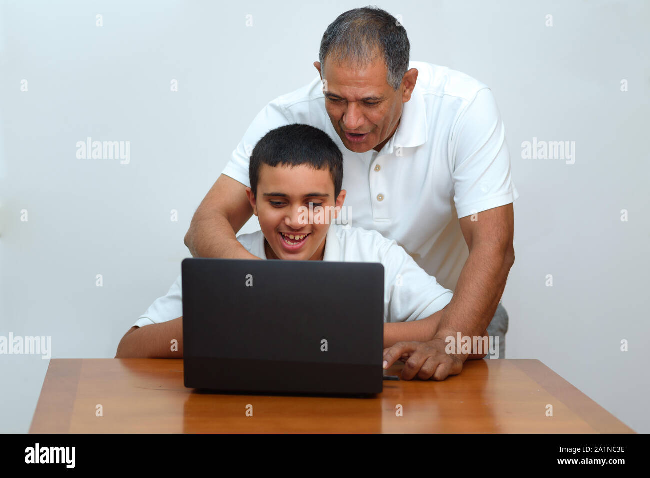 Senior Father and teenage son using laptop. Boy and dad sitting at home ...