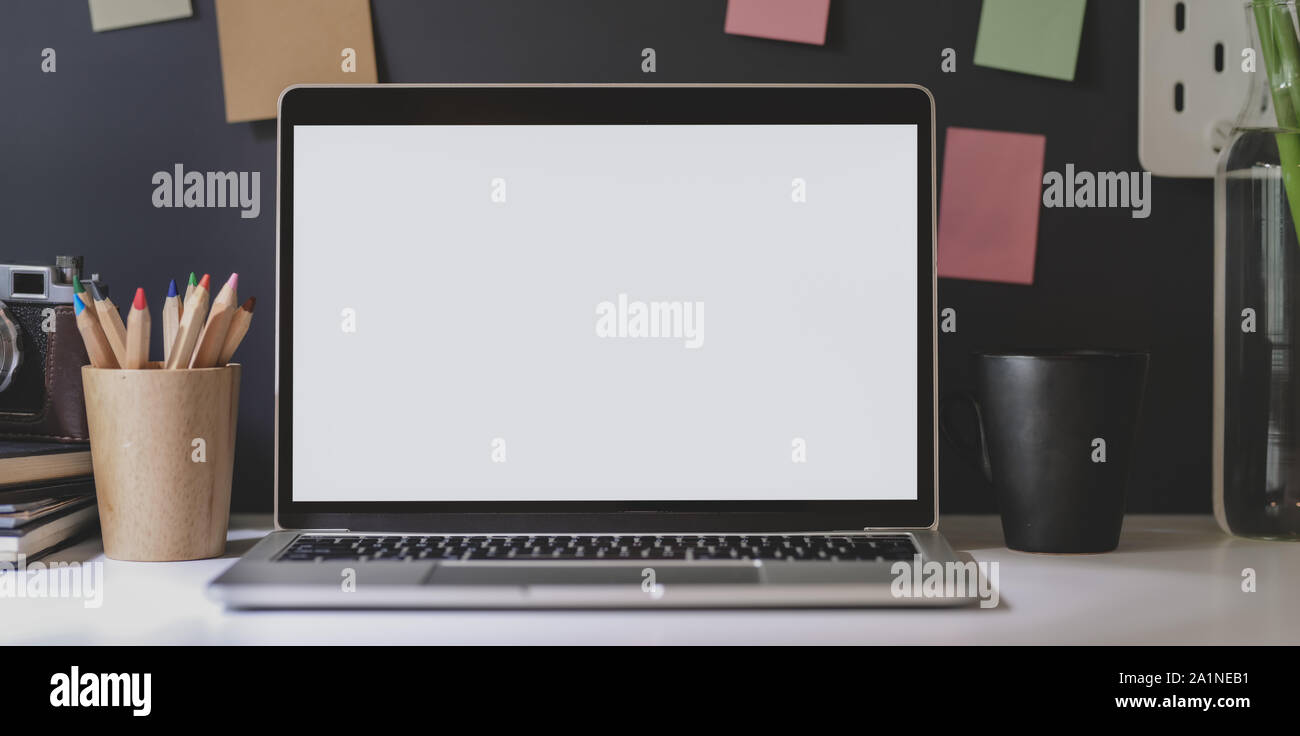 Open blank screen laptop with office supplies in dark trendy workplace ...