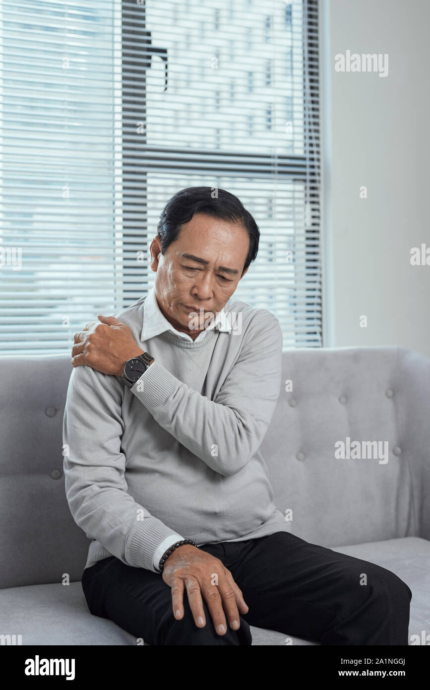 Old senior man with shoulder pain. Grandpa with shoulder inhury at home ...