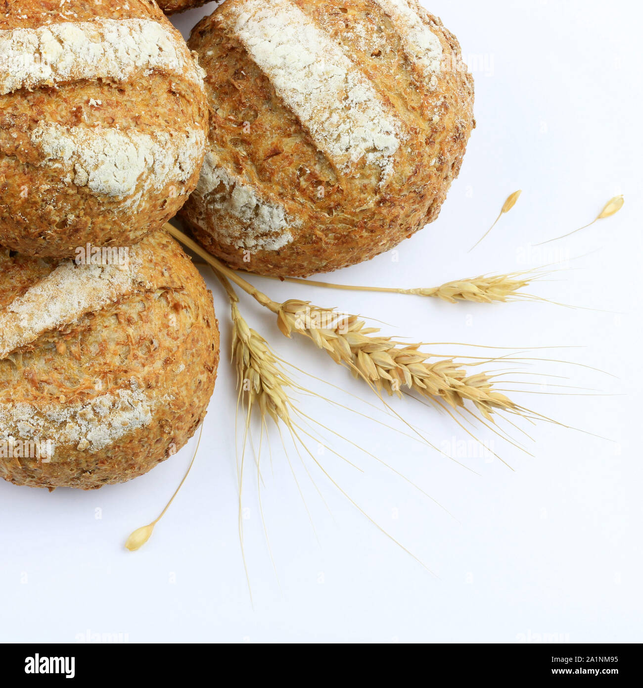Wholemeal oval buns and ears of wheat on a white background Stock Photo ...