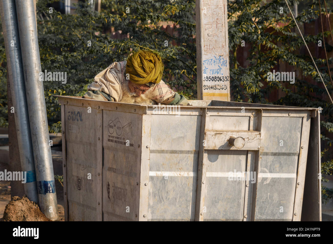Jaisalmer, India - February 14, 2019: Indian man digging in trash bin ...