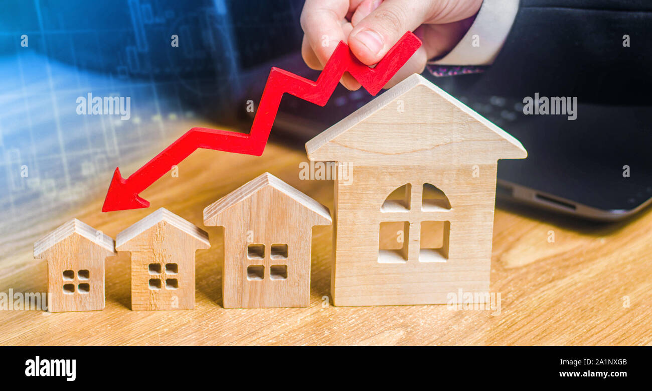 The hand holds a red arrow above the wooden houses down. The houses are ...