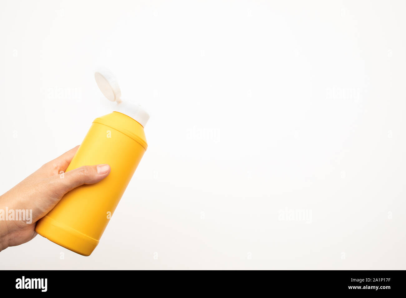 Youngwoman hand squeezing bottle of mustard sauce on white background ...