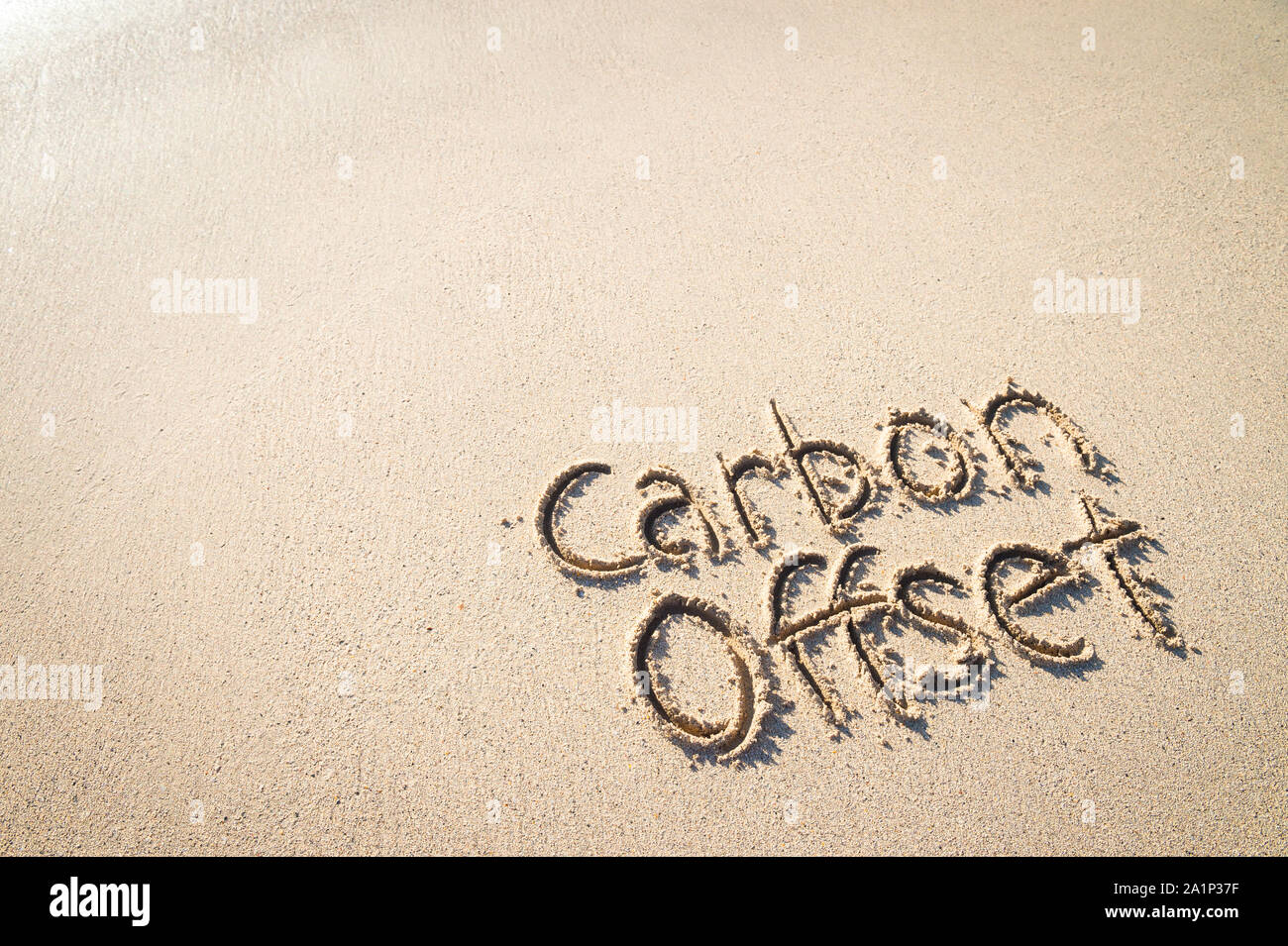 Carbon Offset eco-friendly message handwritten on smooth sand beach ...