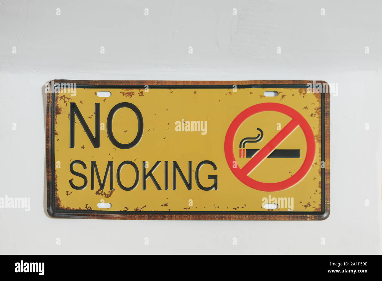 Yellow metal sign NO SMOKING on white wall Stock Photo - Alamy