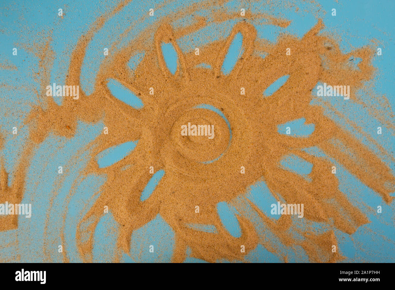 Simple sun drawing on the sand. Sand on blue background Stock Photo - Alamy
