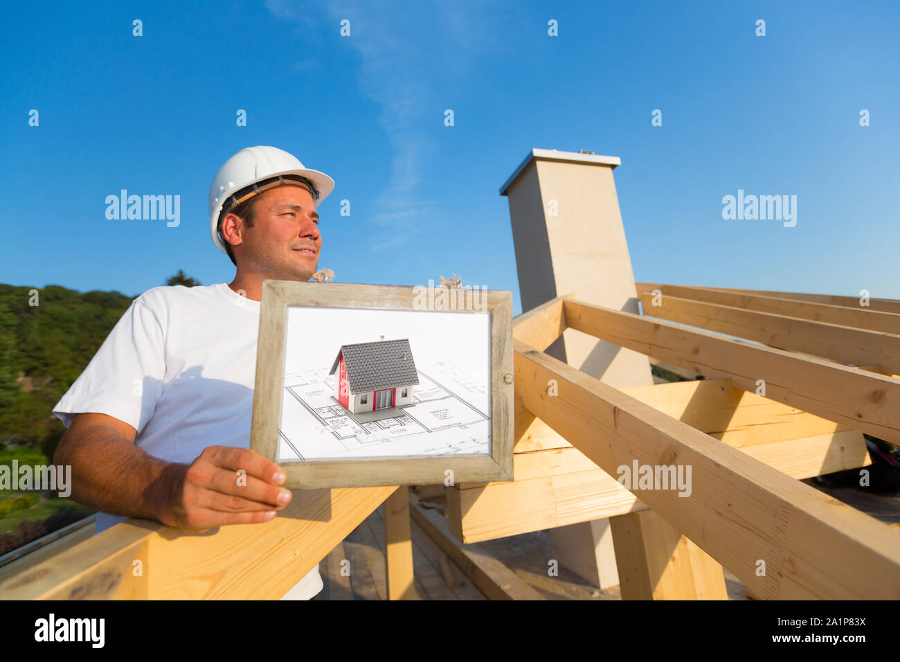 Young architect with blueprint on the top of a house that is currently ...