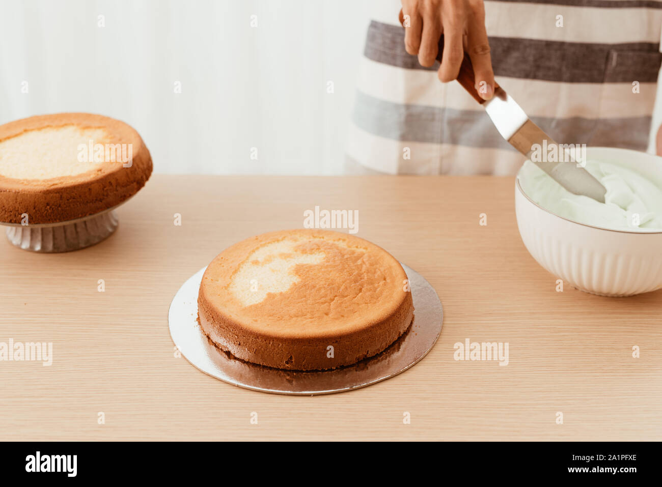pastry chef puts cream on a sponge cake. Cake making process Stock ...