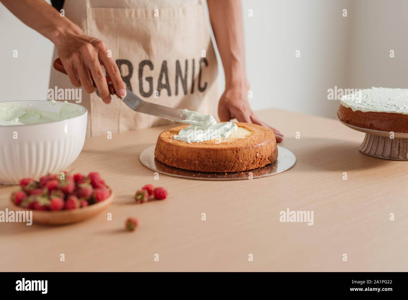 Man pastry chef put icing cream on sponge cake. Making sponge cake ...