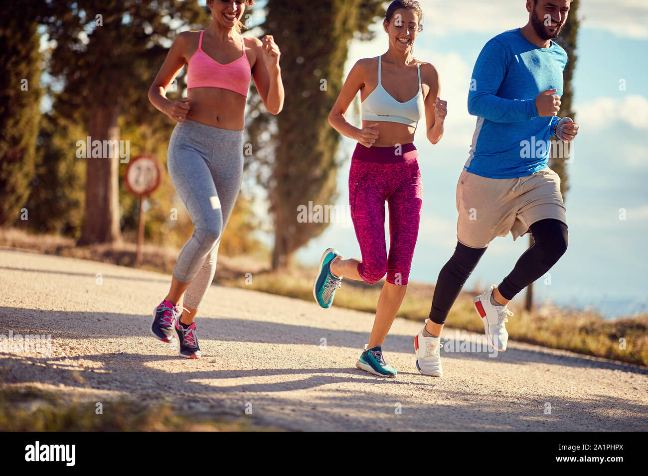 smiling friends running together in nature. Young people exercising ...