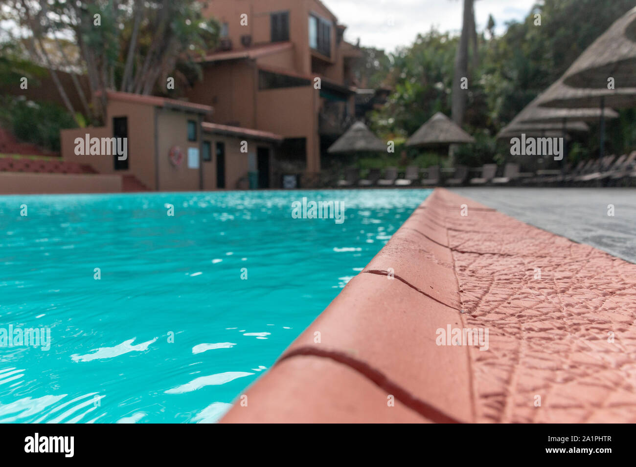A close up view of the side of a large blue water pool Stock Photo - Alamy