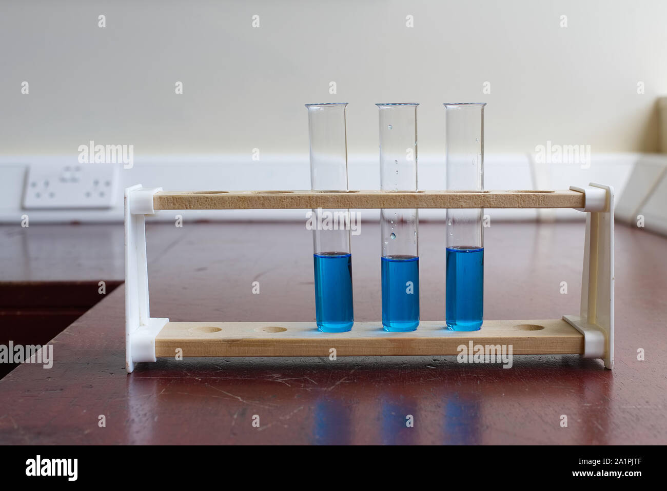 Wooden test tube rack with boiling tube of copper sulfate solution in ...