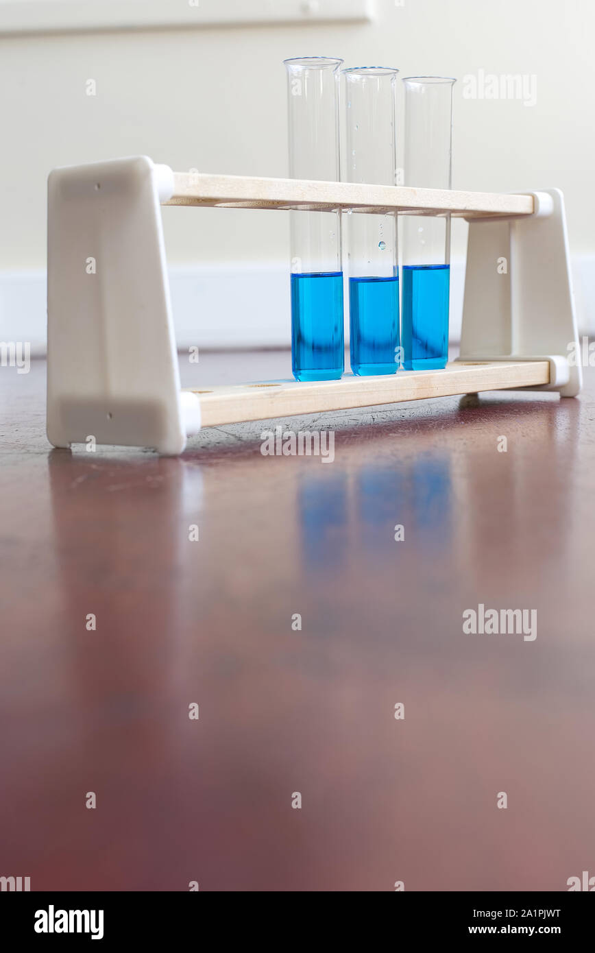 Wooden test tube rack with boiling tube of copper sulfate solution in ...