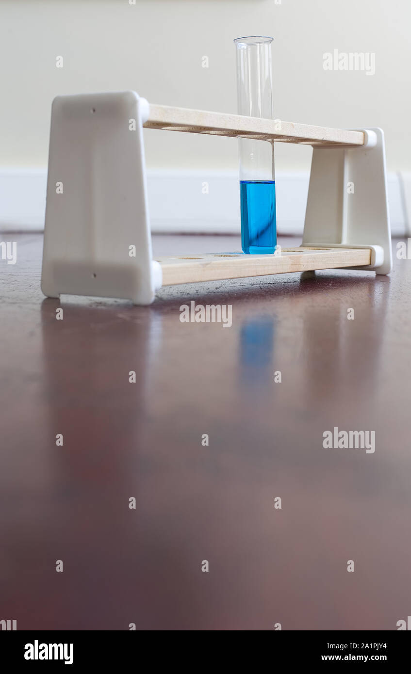 Wooden test tube rack with boiling tube of copper sulfate solution in ...