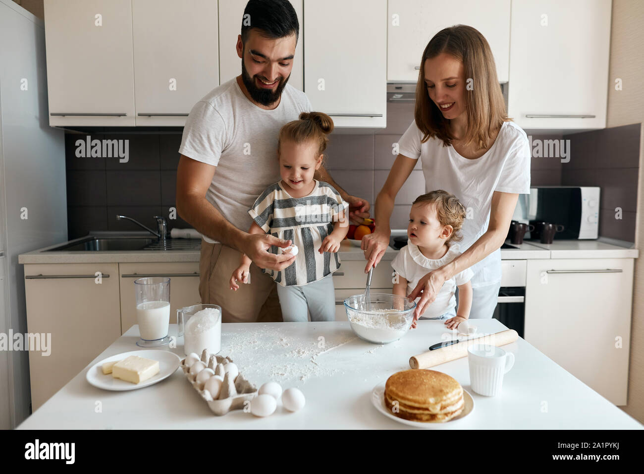 pleasant couple teaching their children to cook, family traditions ...