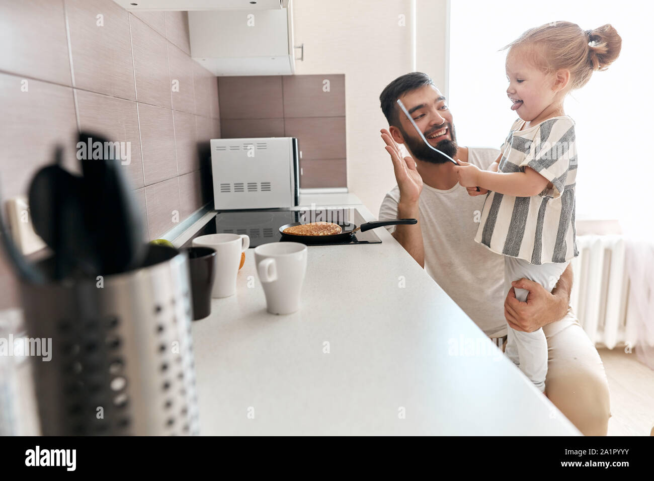 plesant positive dad and his kid having fun in the kitchen while ...