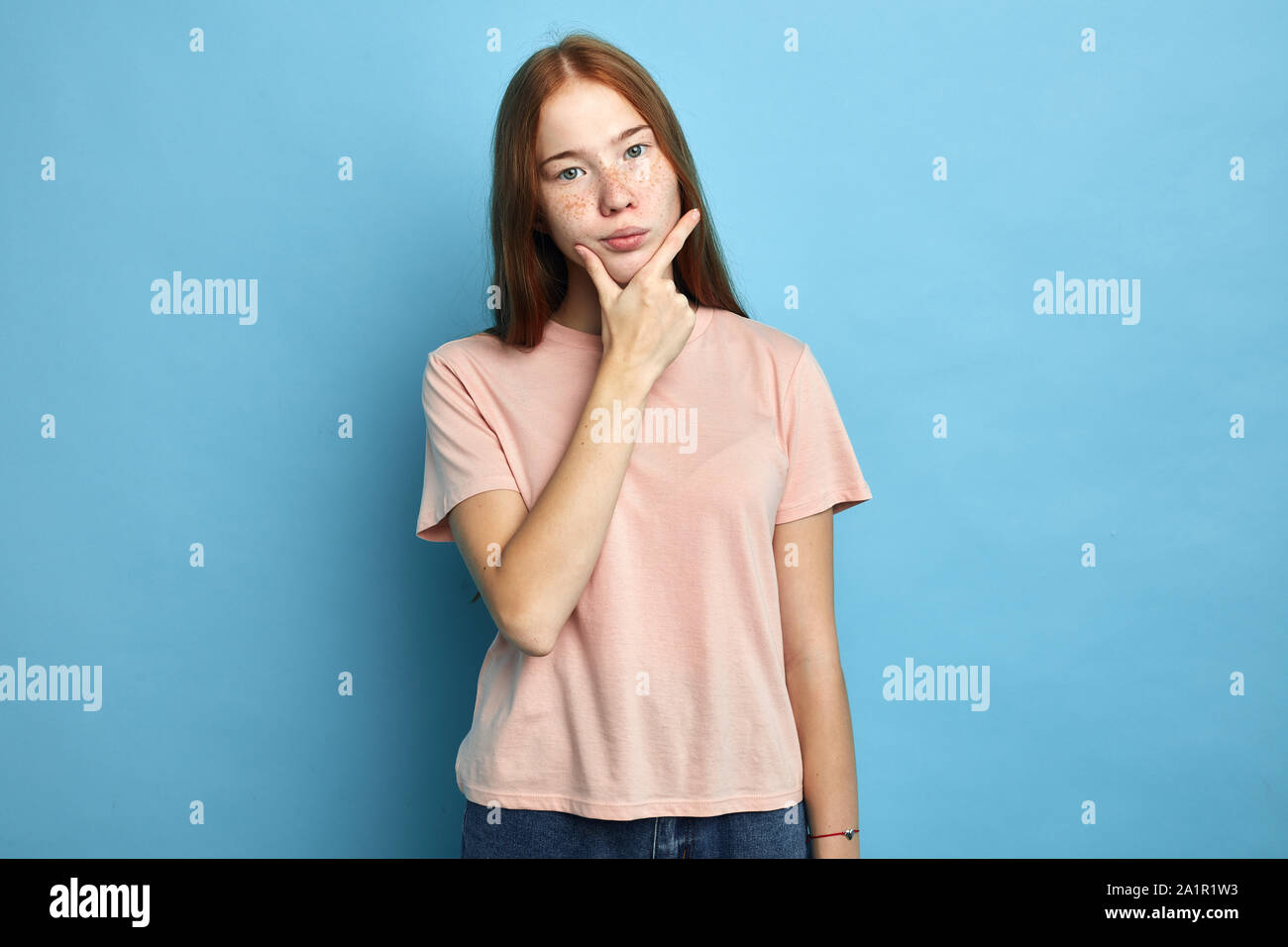 serious teenager with a plm on her chin lookig at the camera, solving ...