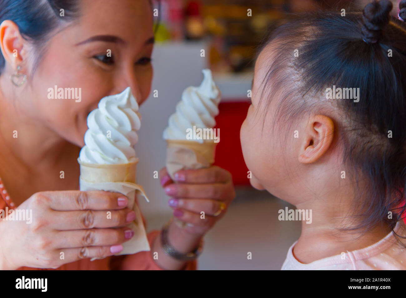 Mom and little child eating ice scream cone together . feeling ...