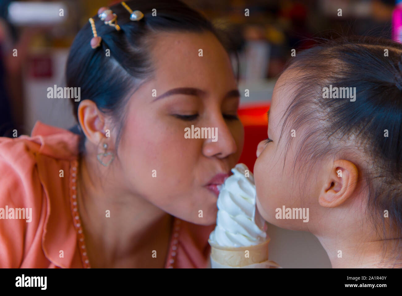 Mom and little child eating ice scream cone together . feeling ...