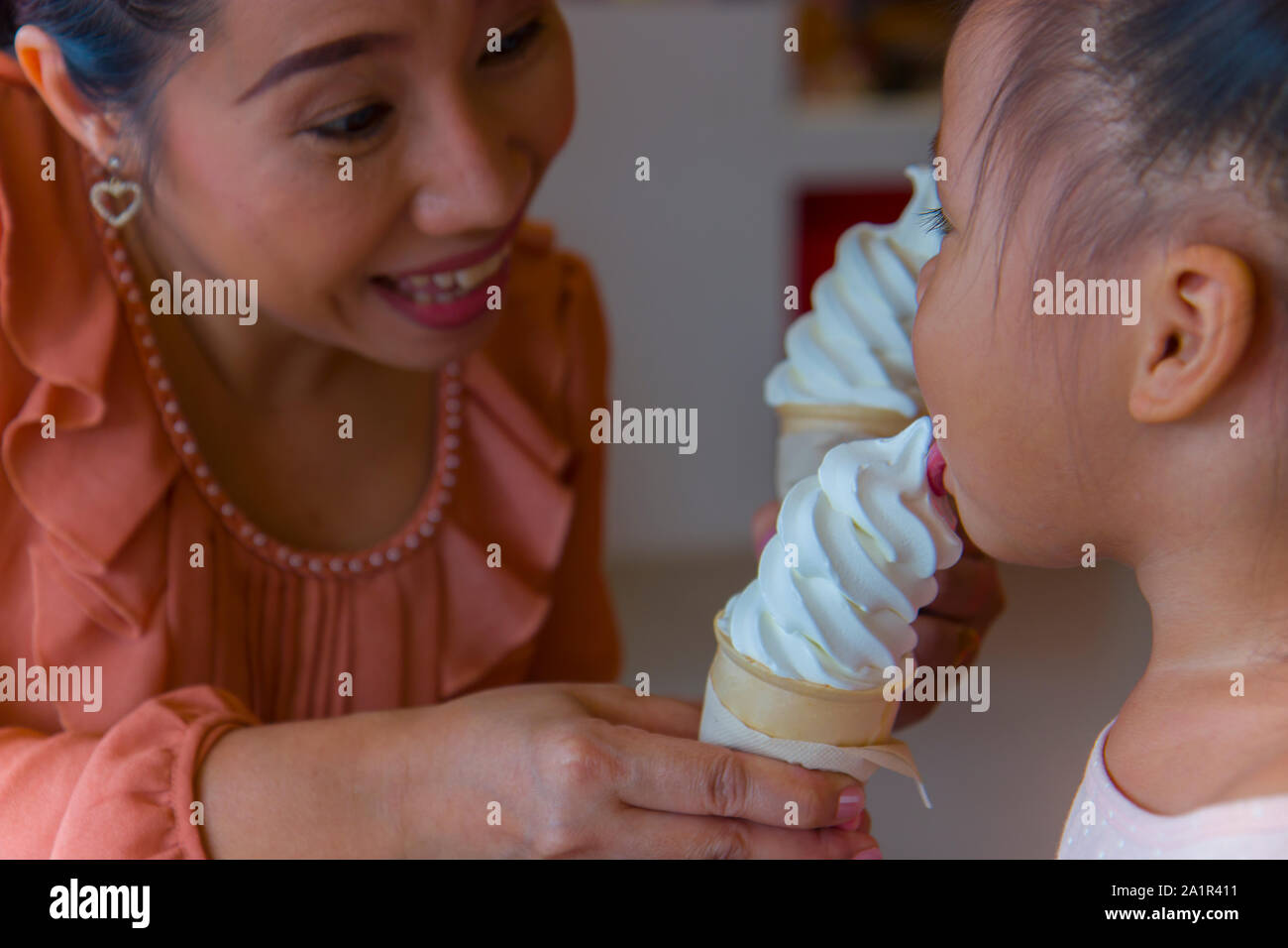 Mom and little child eating ice scream cone together . feeling ...