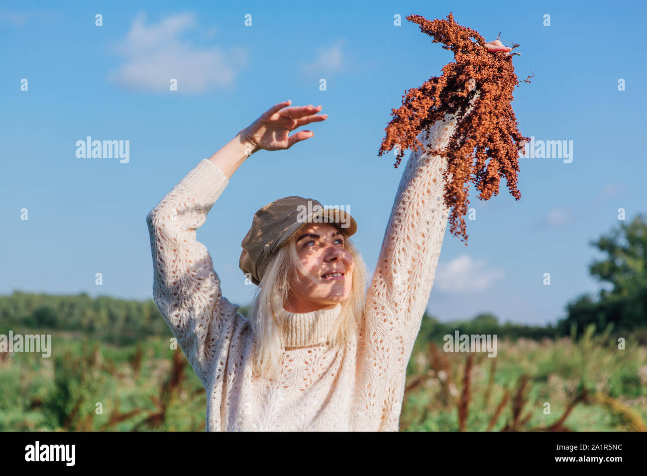 Happy beautiful blond woman dressed in a cap, sweater and white long ...