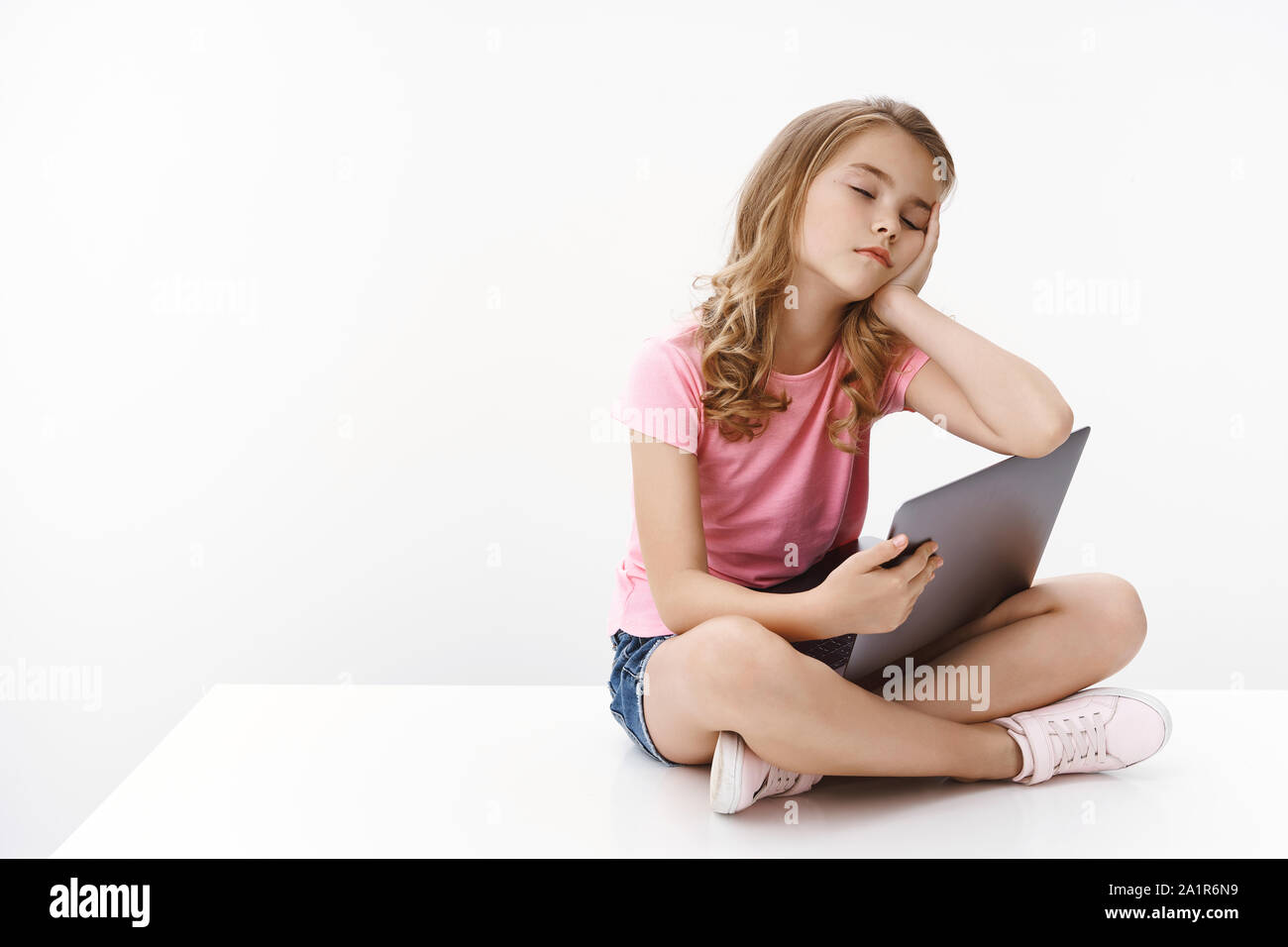 Bored sleepy cute blond girl sit floor laptop, lean on palm and falling ...