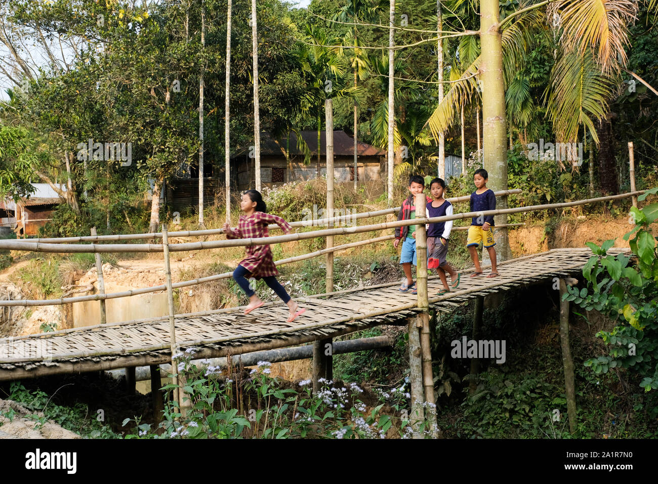 Children run across a wooden bridge in the village of Borakathal ...