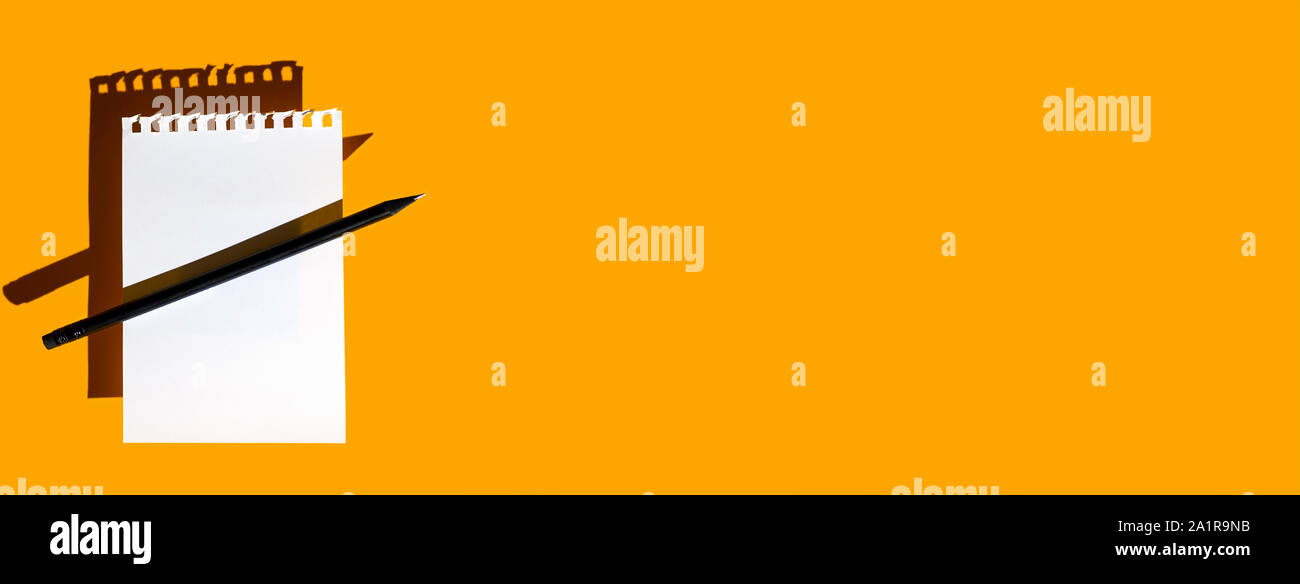 a blank sheet of Notepad, black pencil and hard shadows on a bright ...