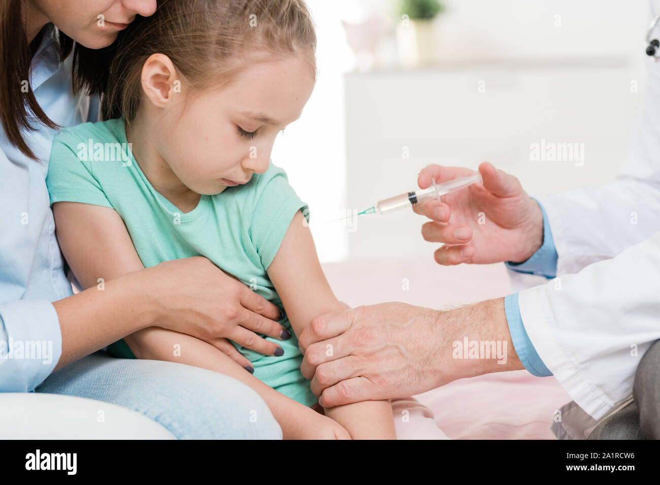 Cute little girl is scared to have injection while looking at syringe ...