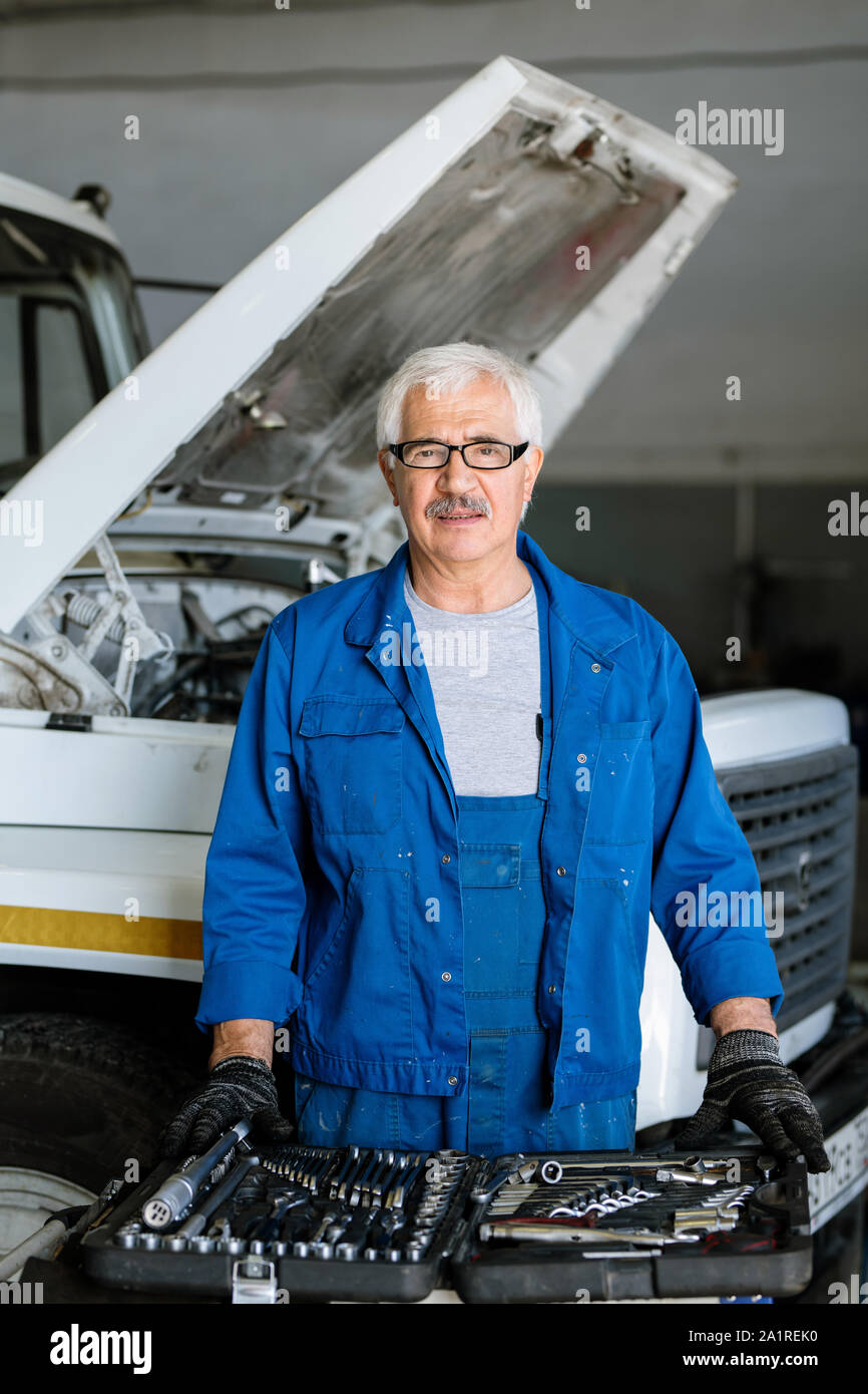 Mature technician with grey hair choosing worktools while serving one ...