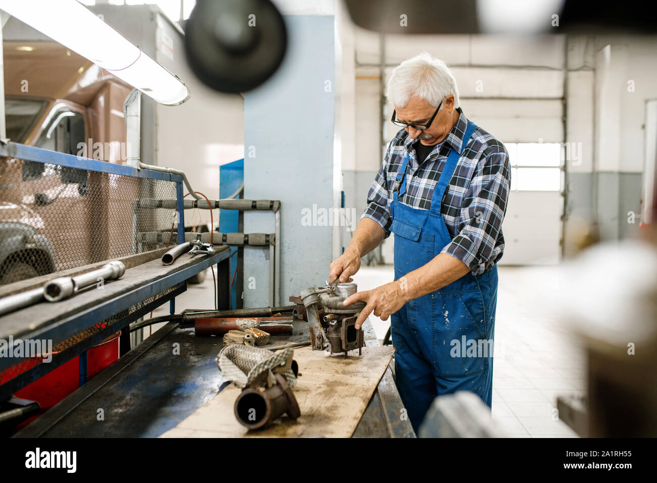 Mature professional repairman of car maintenance service standing by ...