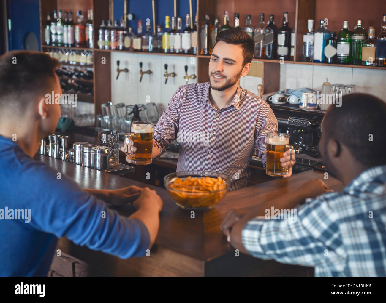 Bartender Giving Glasses With Beer To Young Guys Stock Photo - Alamy