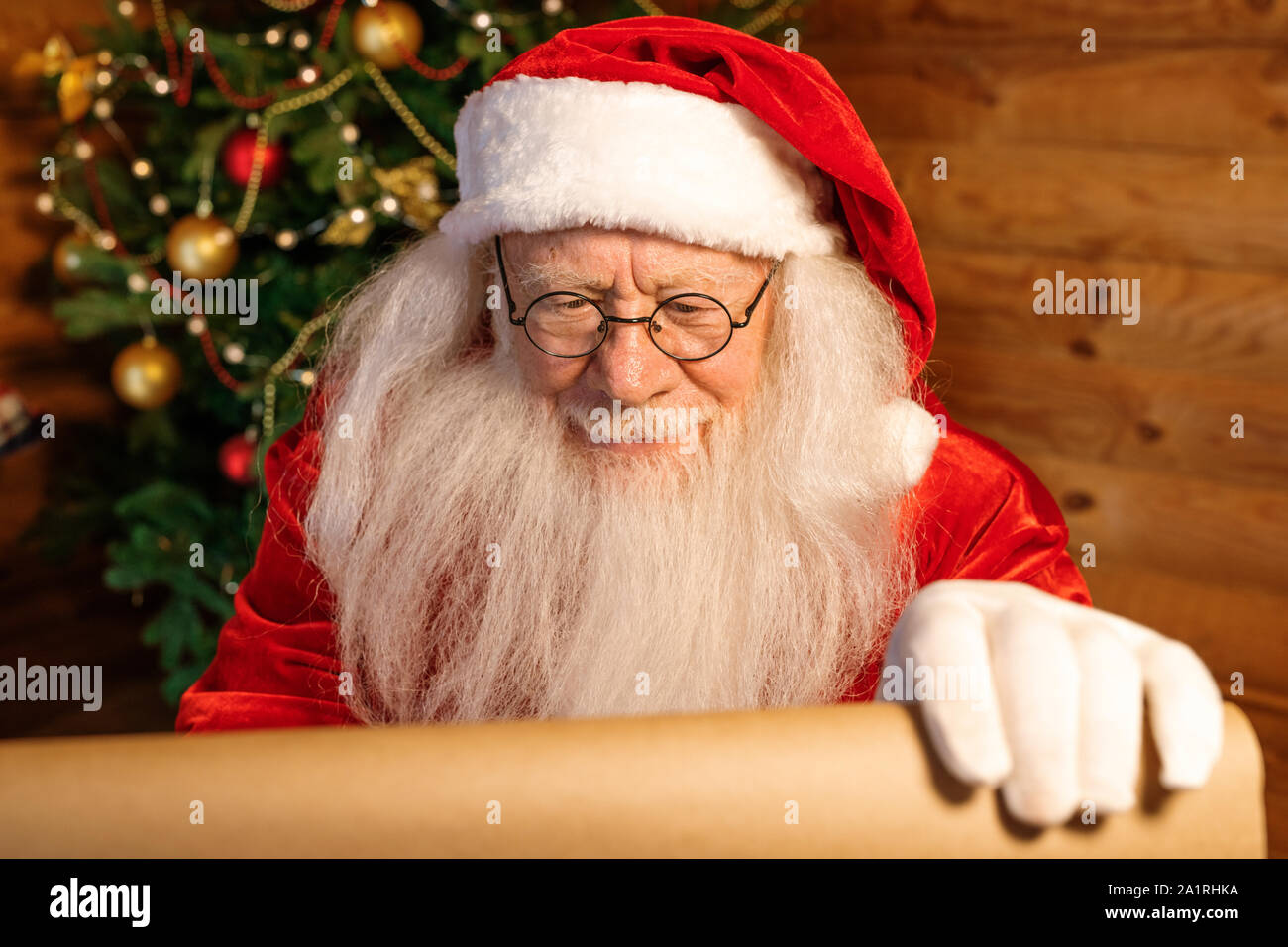 Contemporary Santa Claus in costume and eyeglasses holding paper with ...