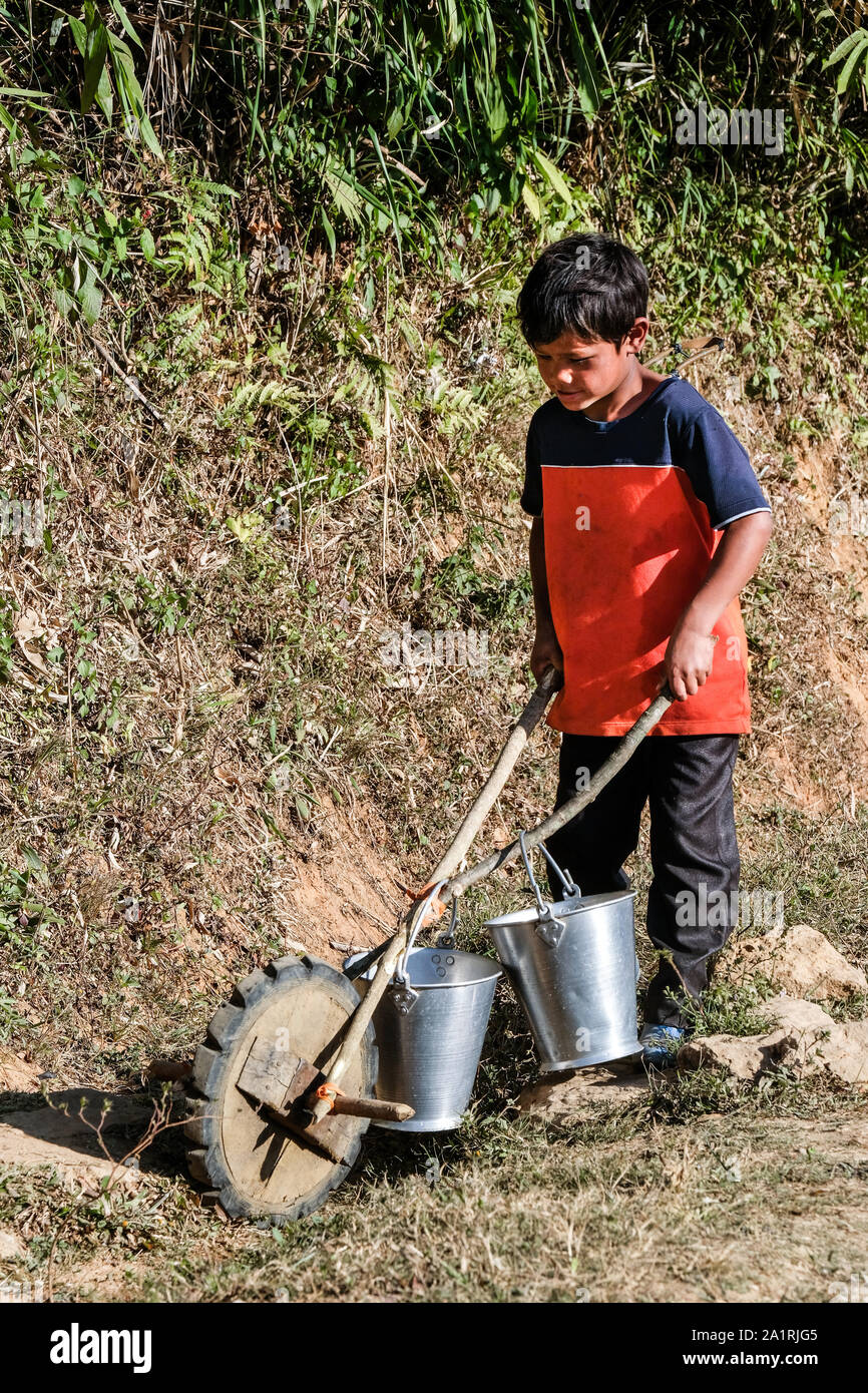 Boy is carrying water buckets with his wheelbarrow from a nearby ...