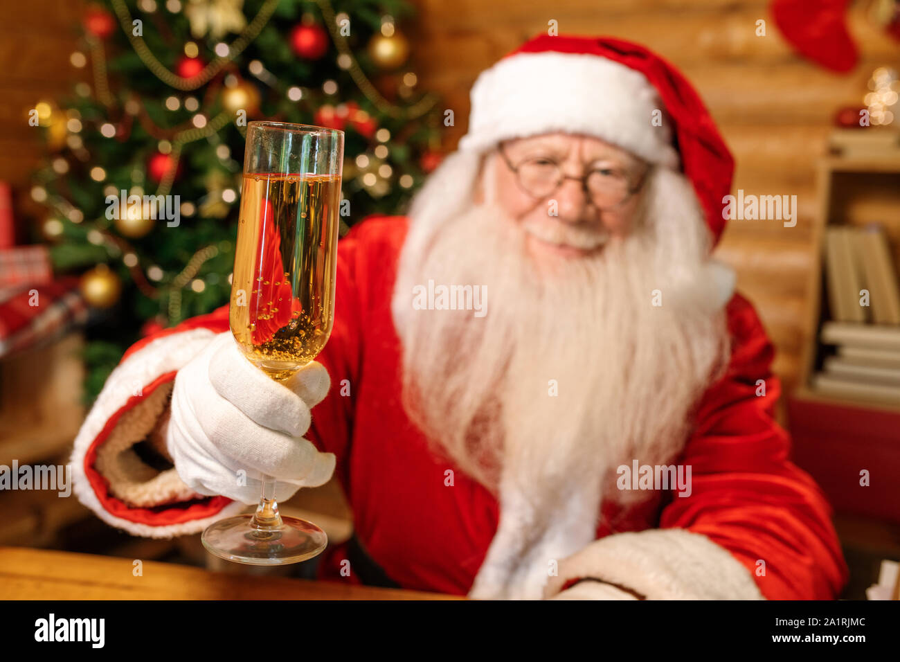 Happy Santa Claus cheering with flute of champagne in front of camera ...