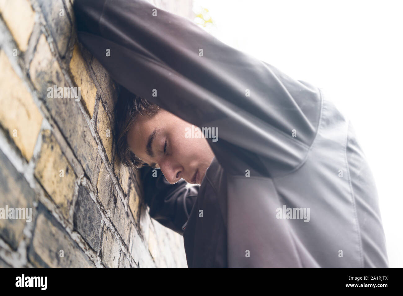 young man standing with his head against the wall Stock Photo - Alamy